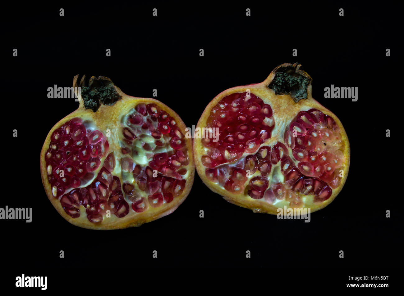 a split pomegranate isolated on black background Stock Photo - Alamy