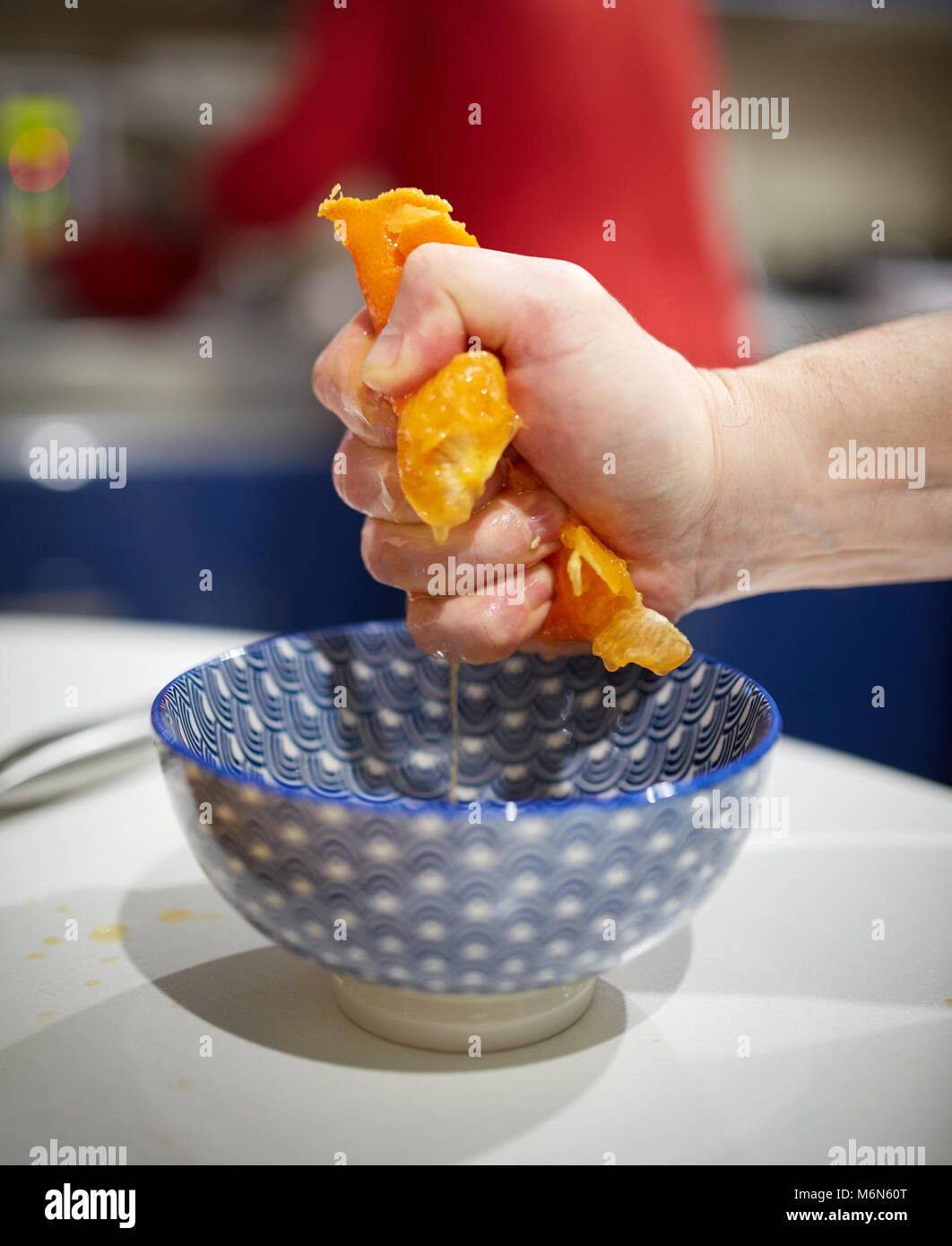 Man's hand furiously squashing an orange into a bowl Stock Photo - Alamy