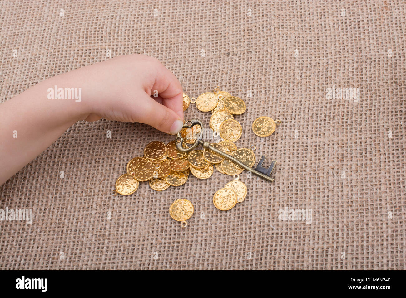 Hand holding a retro styled key over fake gold coins Stock Photo - Alamy