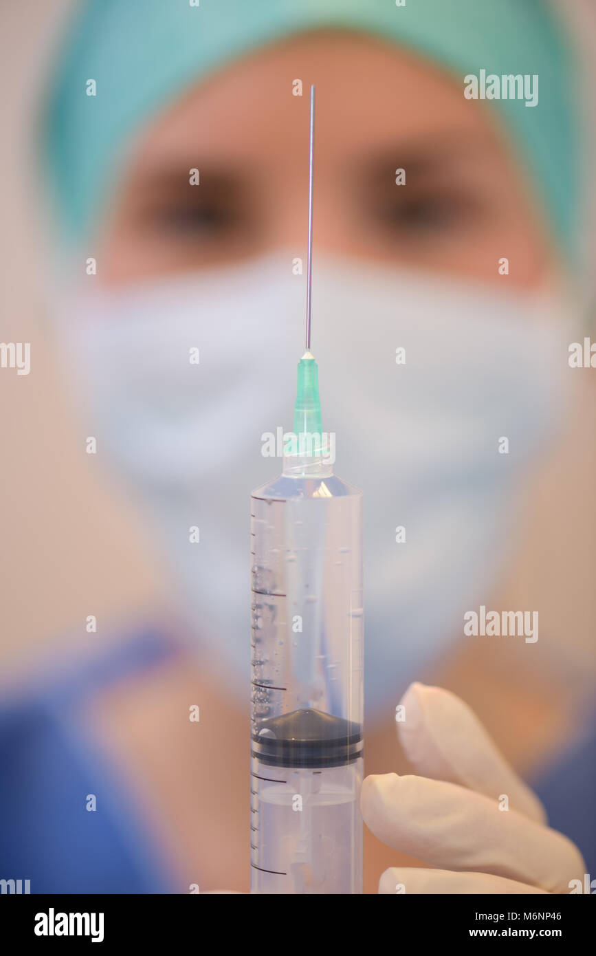 Close up of syringe held by masked medic Stock Photo - Alamy