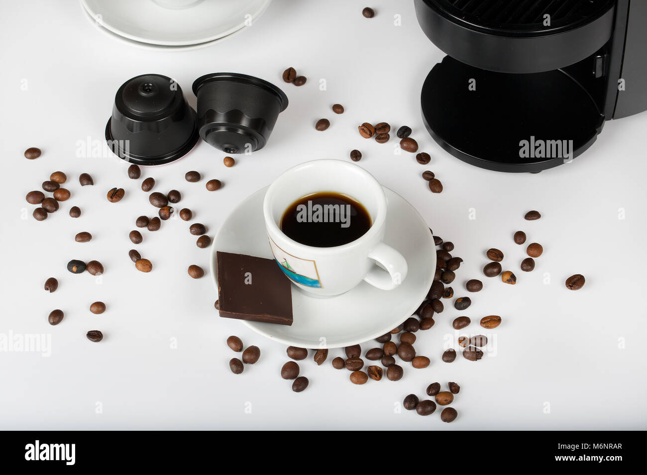 Cup of short espresso,coffee capsules and beans on a white surface ...