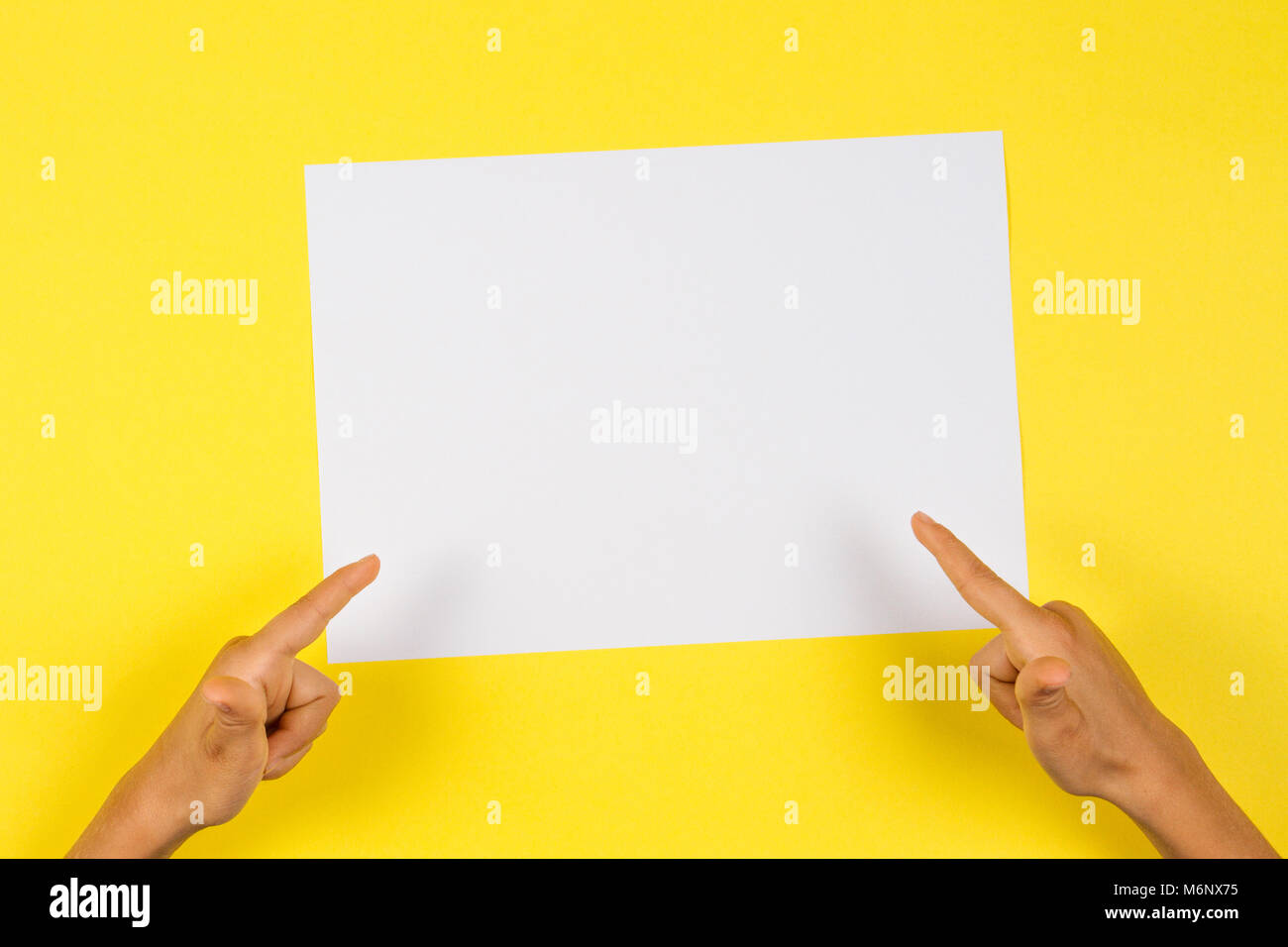 Kids hands fingers pointing to white blank paper card on yellow ...