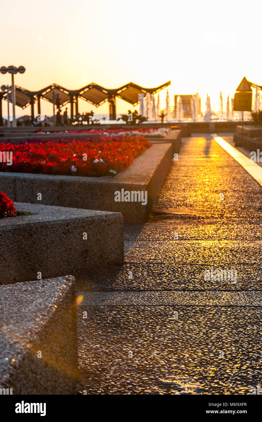 Sunset sun through the beach fountain flows on Mediterranean sea coast ...