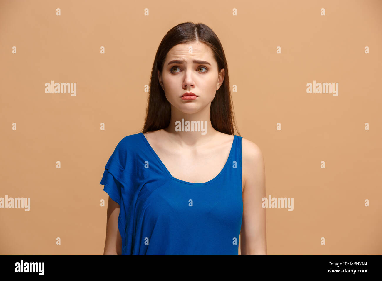 The awkward woman standing and looking at camera against pastel ...