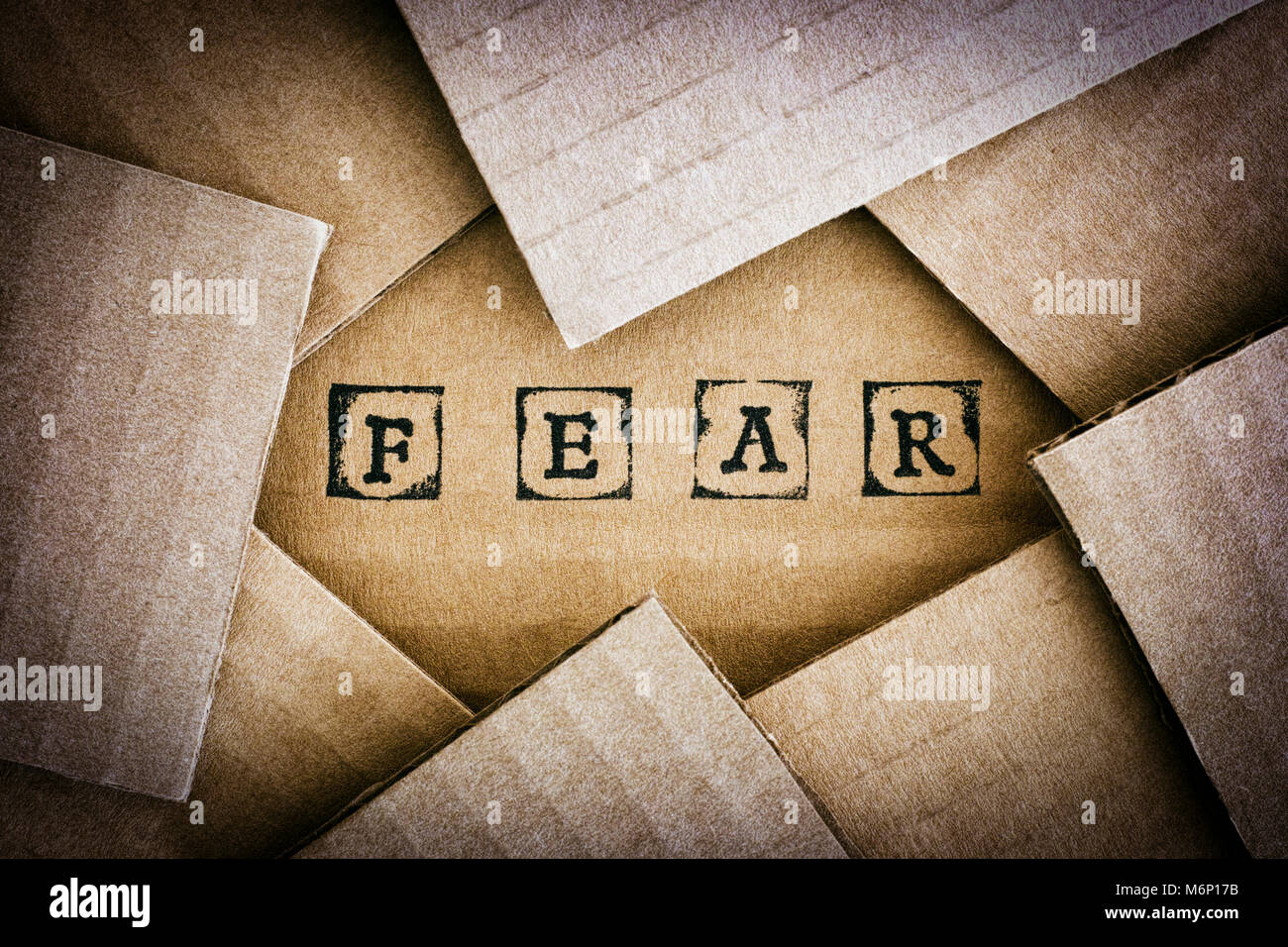 Word Fear make by black alphabet stamps on cardboard with some piece of ...