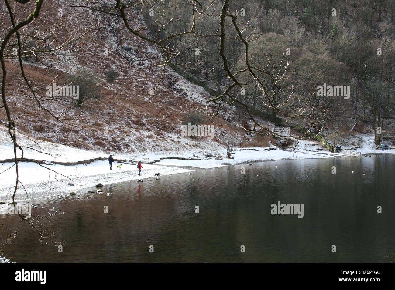 people walking along a snow covered shoreline at Grasmere Lake in the ...