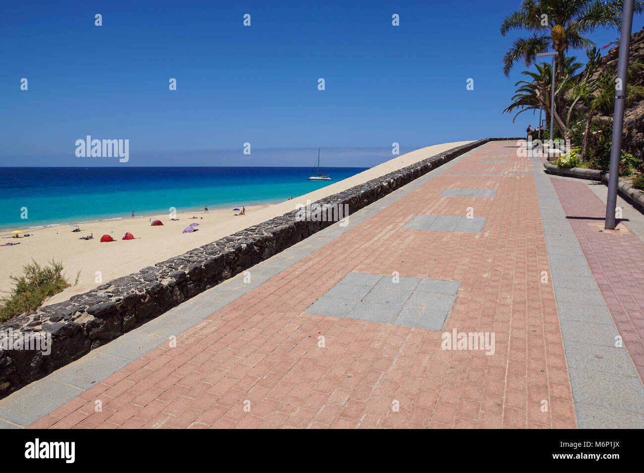 Promenade with tropical plants and flowers along a beach in Morro Jable ...