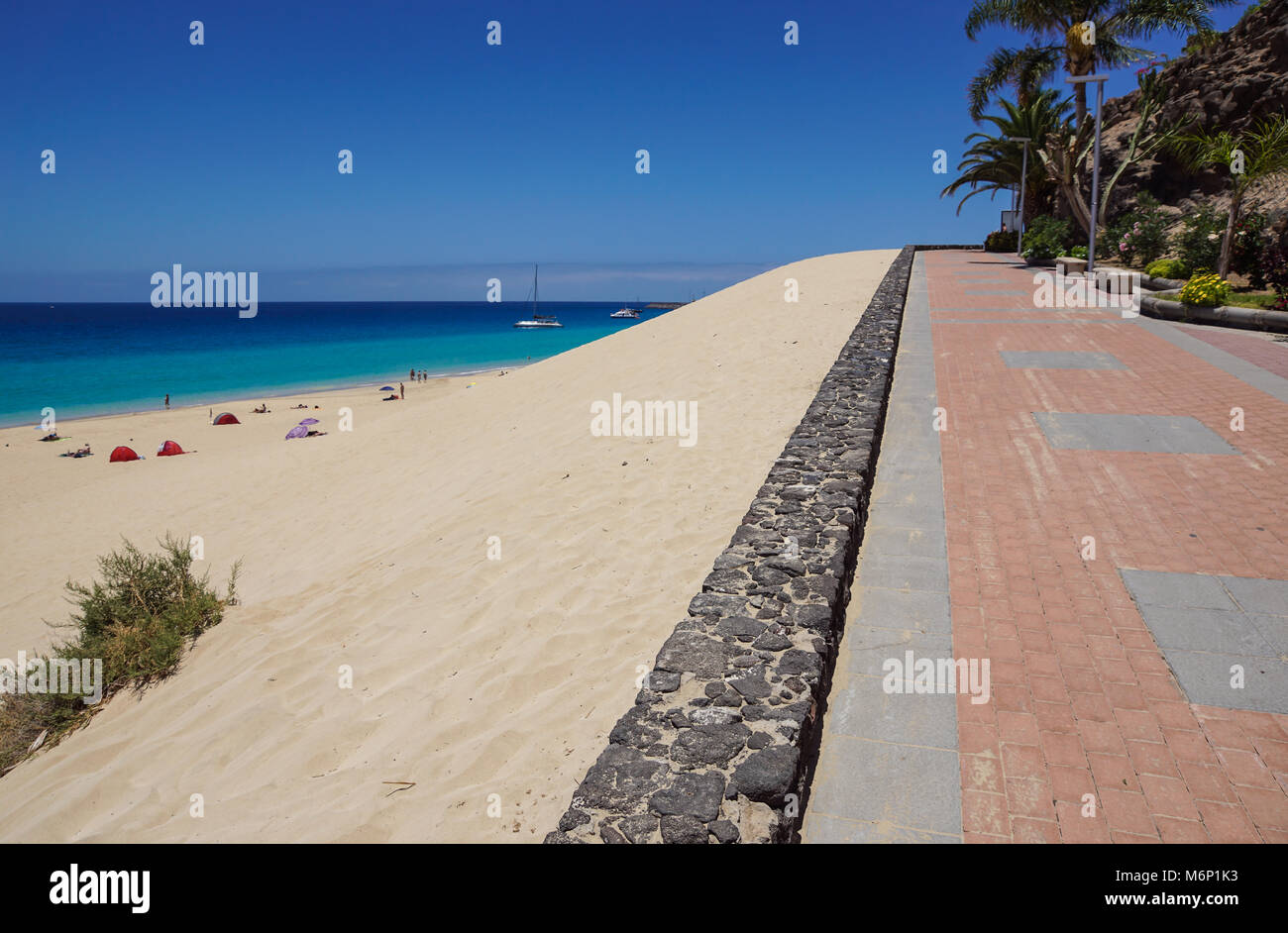 Promenade with tropical plants and flowers along a beach in Morro Jable ...