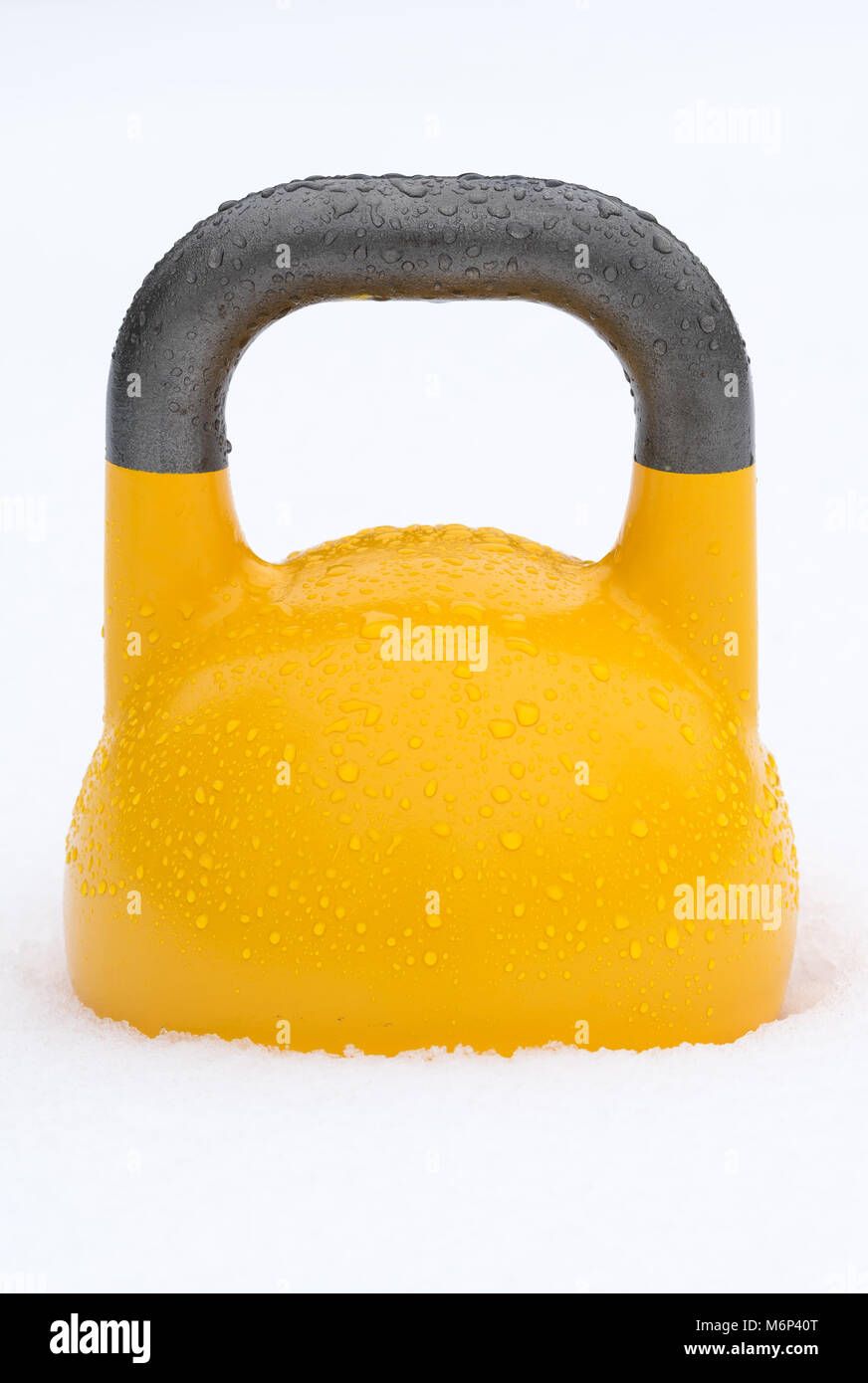 Yellow weight training kettlebell outside in the snow. Green ...