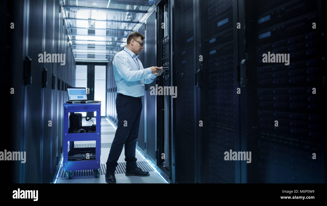 IT Engineer Installing Hard Drives into Working Rack Server. He's ...