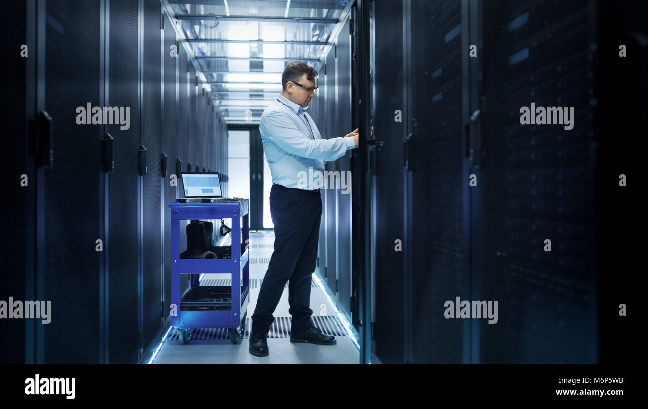 IT Engineer Installing Hard Drives into Working Rack Server. He's ...