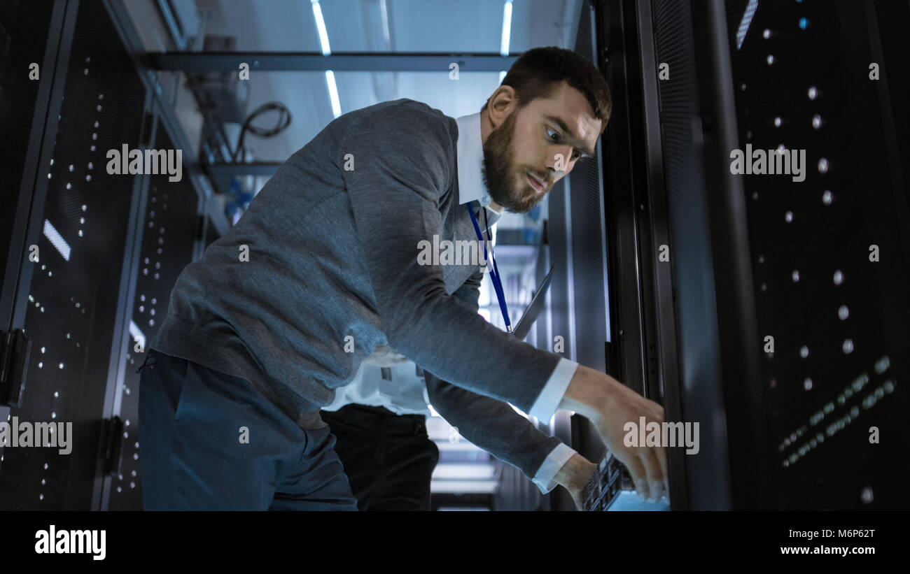 Male Server Engineer Takes Out Components from Server Rack Cabinet. He ...