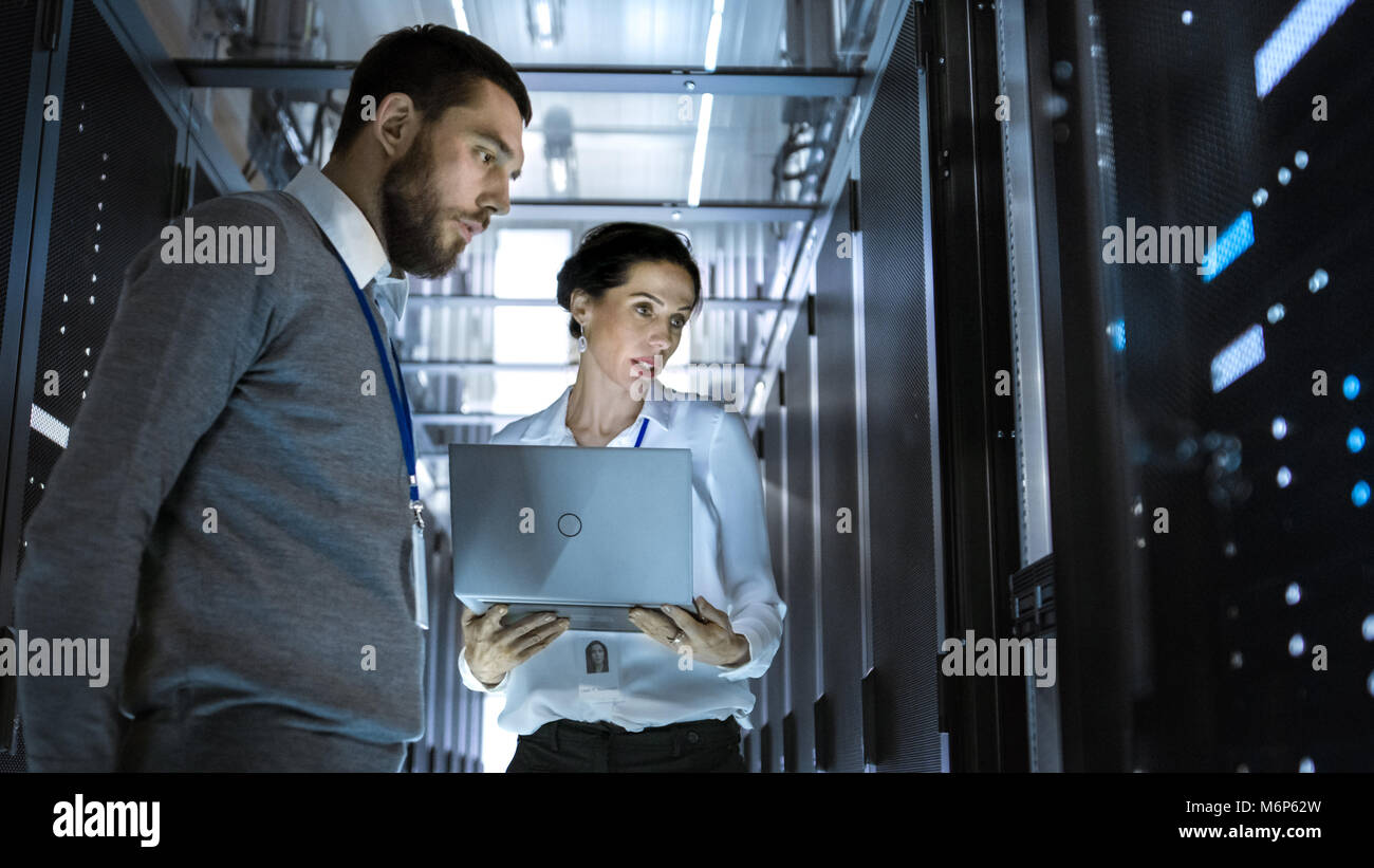 Male Server Engineer is Looking at Server Rack Cabinet. His Female ...
