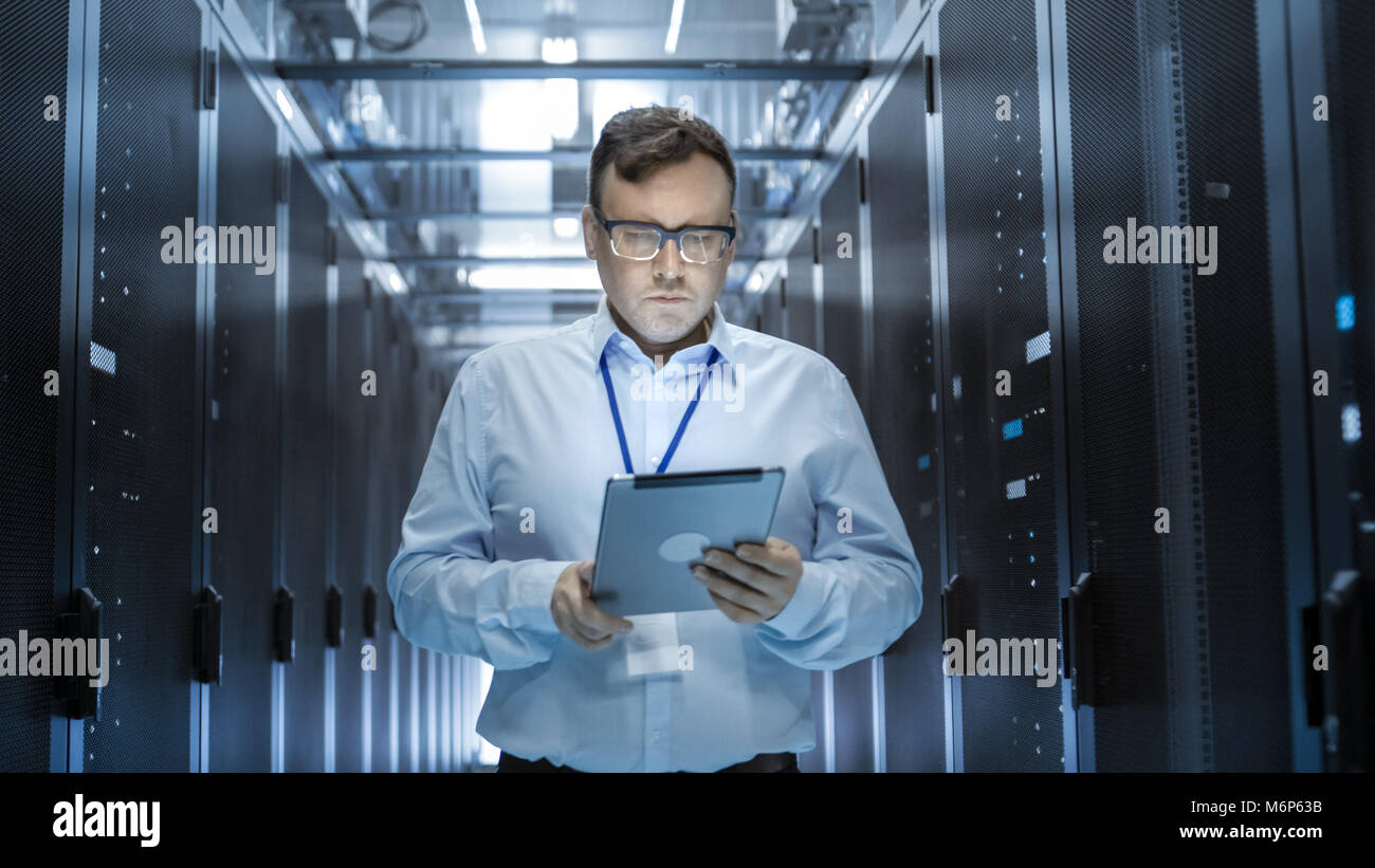 It Technician Walks Through Rows Of Server Racks In Data Center Simultaneously He Works On A