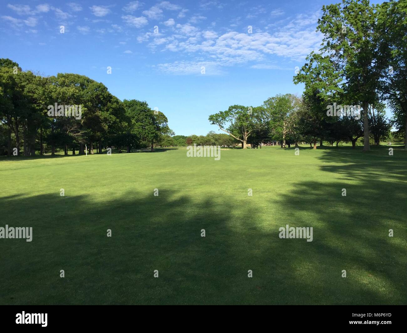 Bright sunlight casts tree shadows across the fairway of a wide open ...