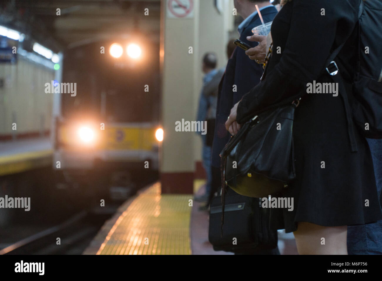 Passengers wait for railroad train to arrive at station platform to ...