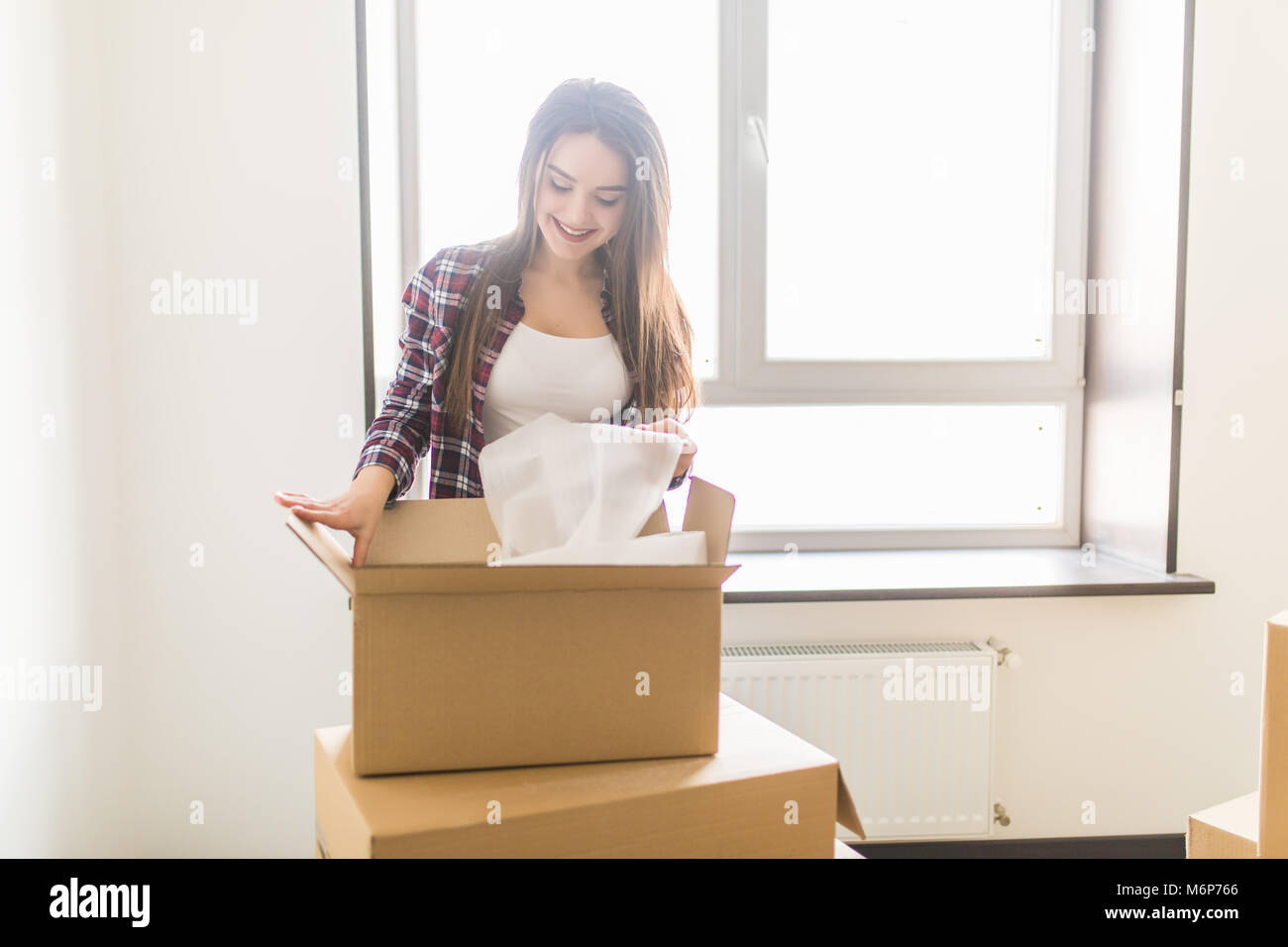 Happy young woman unpacking boxes in new home Stock Photo - Alamy