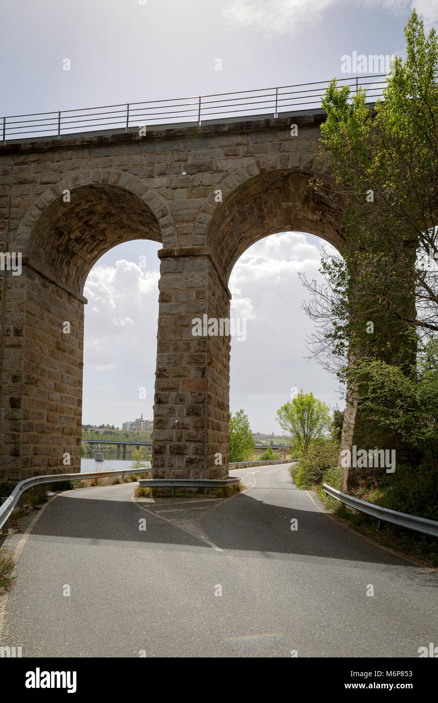 Road passing through the eyes of an old stone bridge for the railway ...