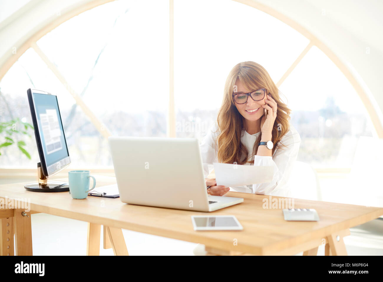 Executive businesswoman doing some paperwork and making call while ...