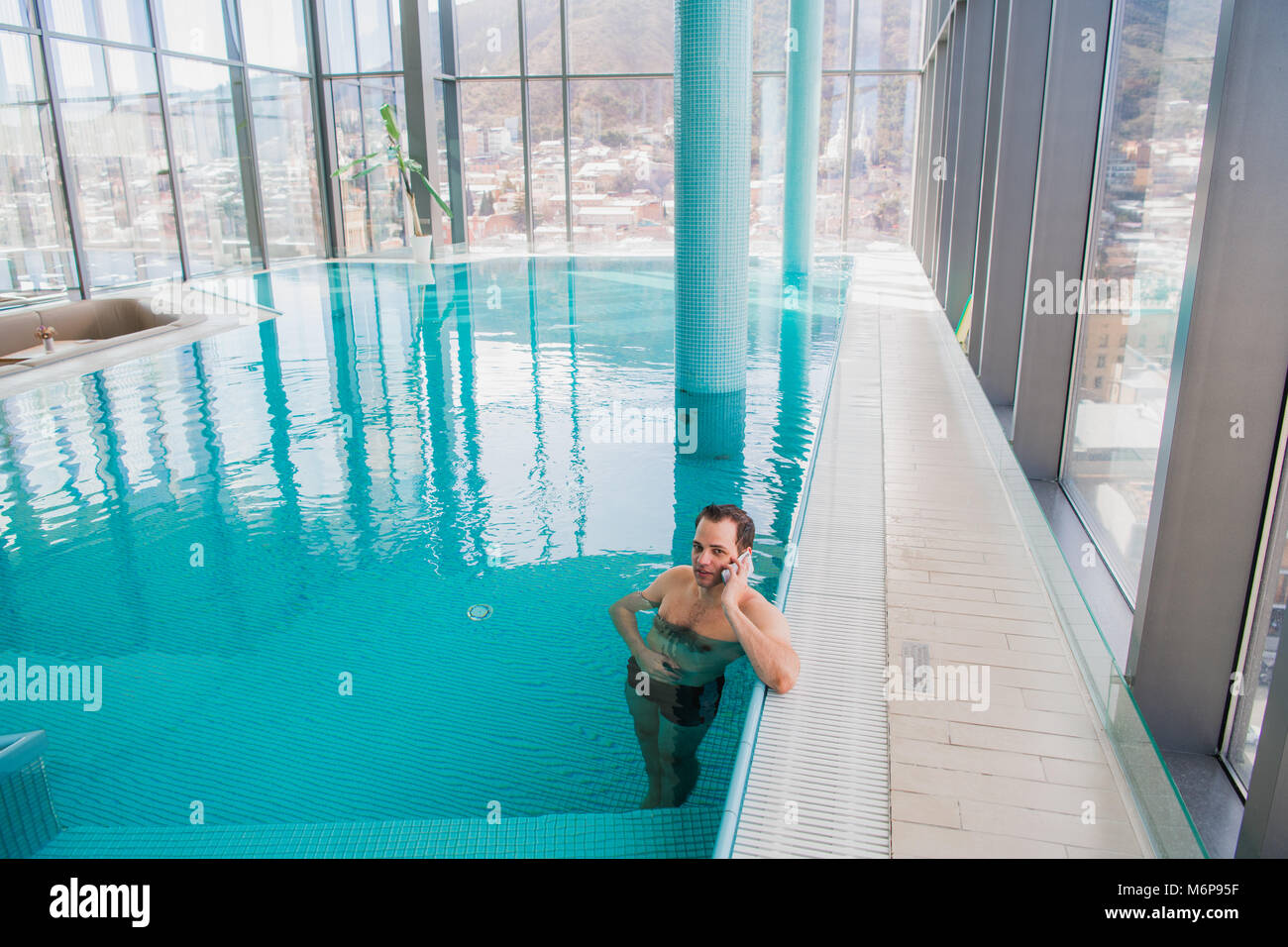 Man talking on cell phone inside the swimming pool at luxury hotel ...