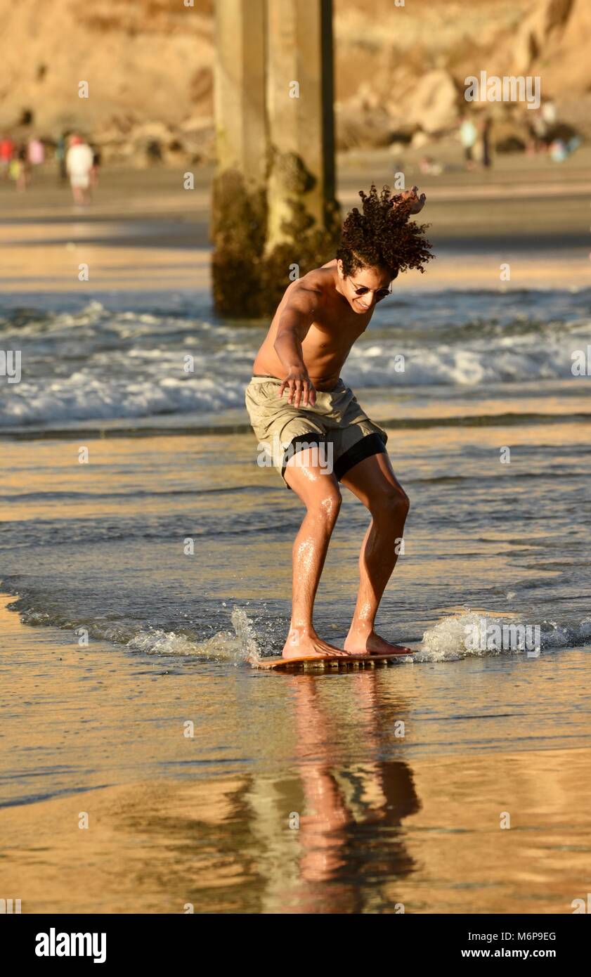 Young African-American man on a skim board, skimming, at beach during ...