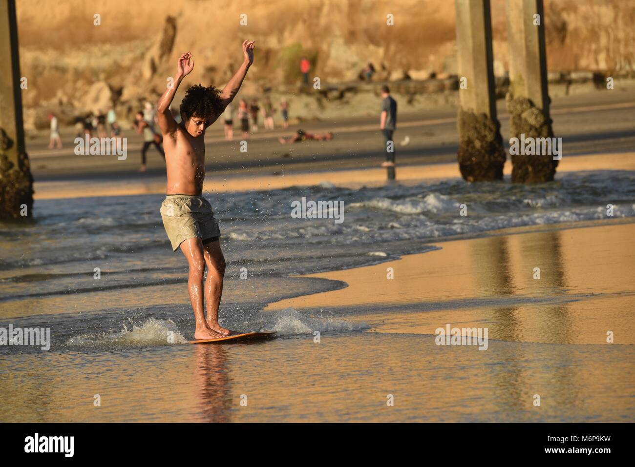 Young African-American man on a skim board, skimming, at beach during ...