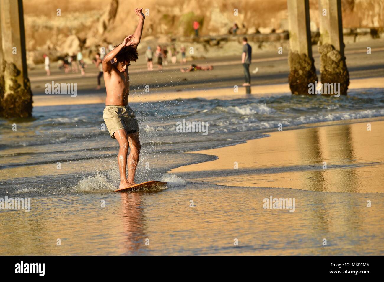 Young African-American man on a skim board, skimming, at beach during ...