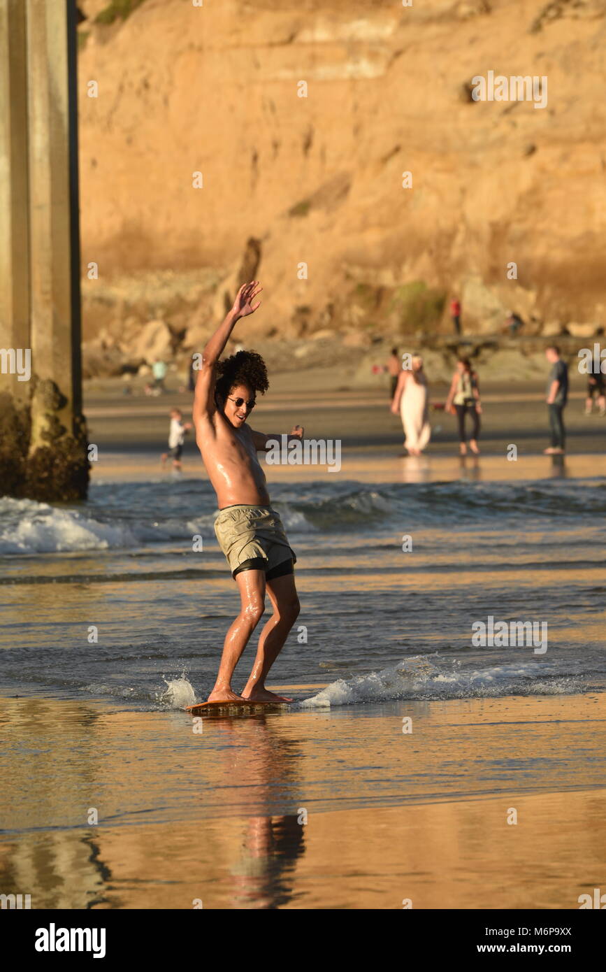 Young African-American man on a skim board, skimming, at beach during ...