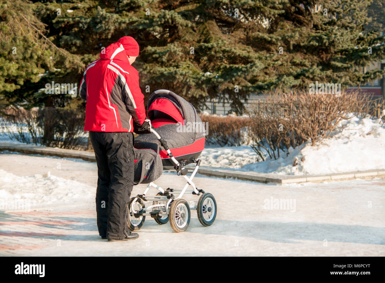 Man with baby stroller walks through the winter park Stock Photo - Alamy