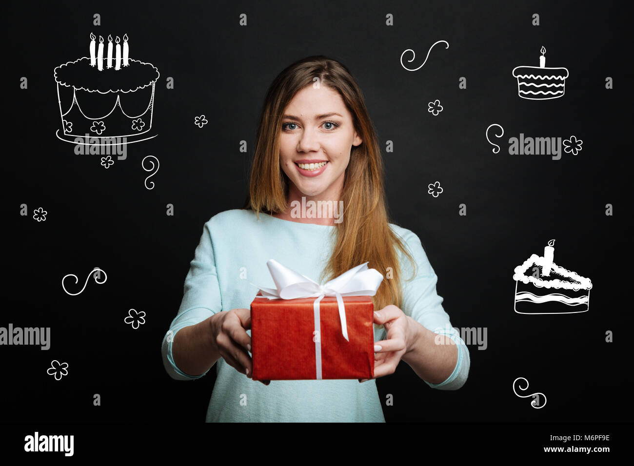 Cheerful young woman giving a nice present and kindly smiling Stock ...