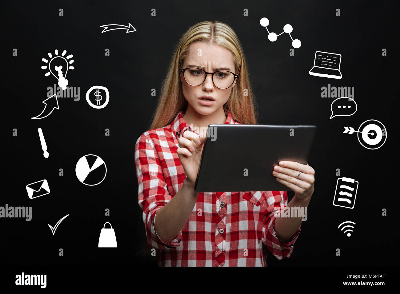 Surprised student frowning while looking at the screen of her tablet ...