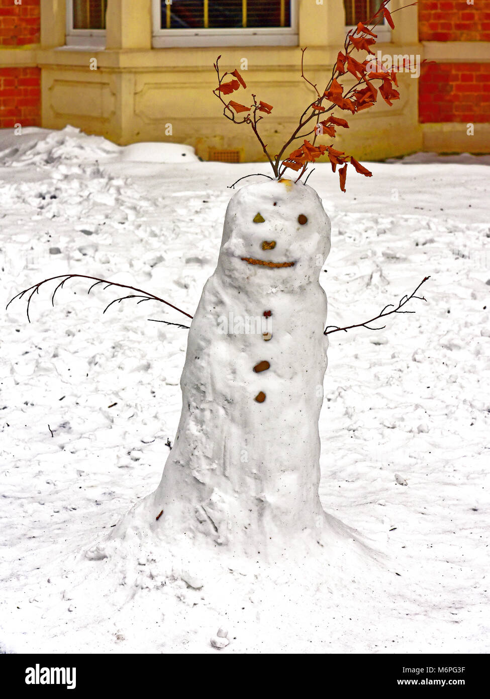 Snowman with twig arms and mouth and stone eyes Stock Photo - Alamy