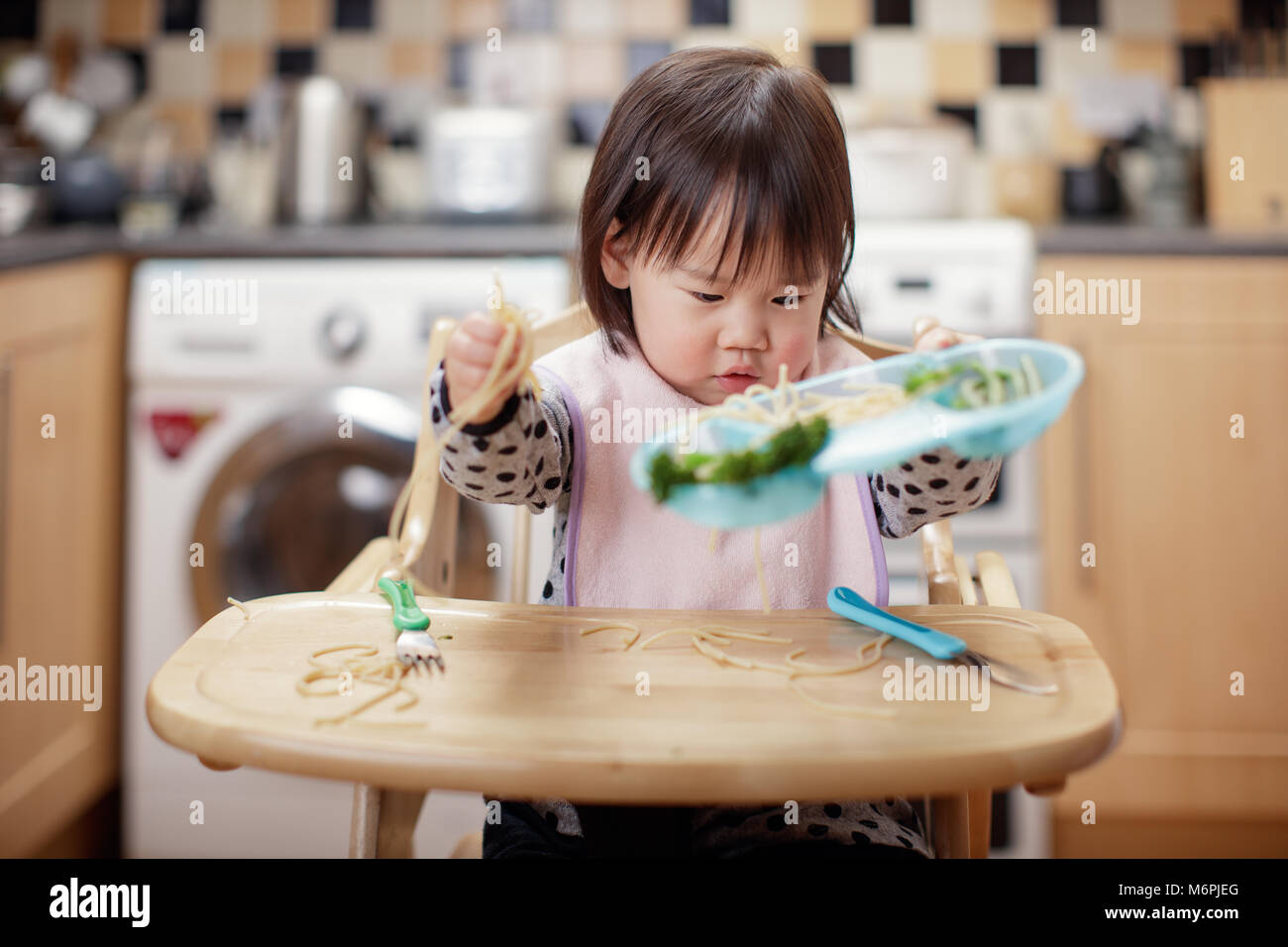 Baby girl eating messy at home kitchen Stock Photo - Alamy