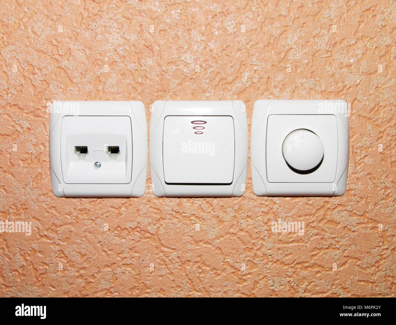 switch the light switch on the wall of orange wallpaper Stock Photo - Alamy