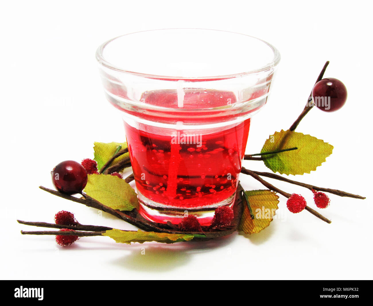 Red scented candle in a glass and green branches Stock Photo - Alamy
