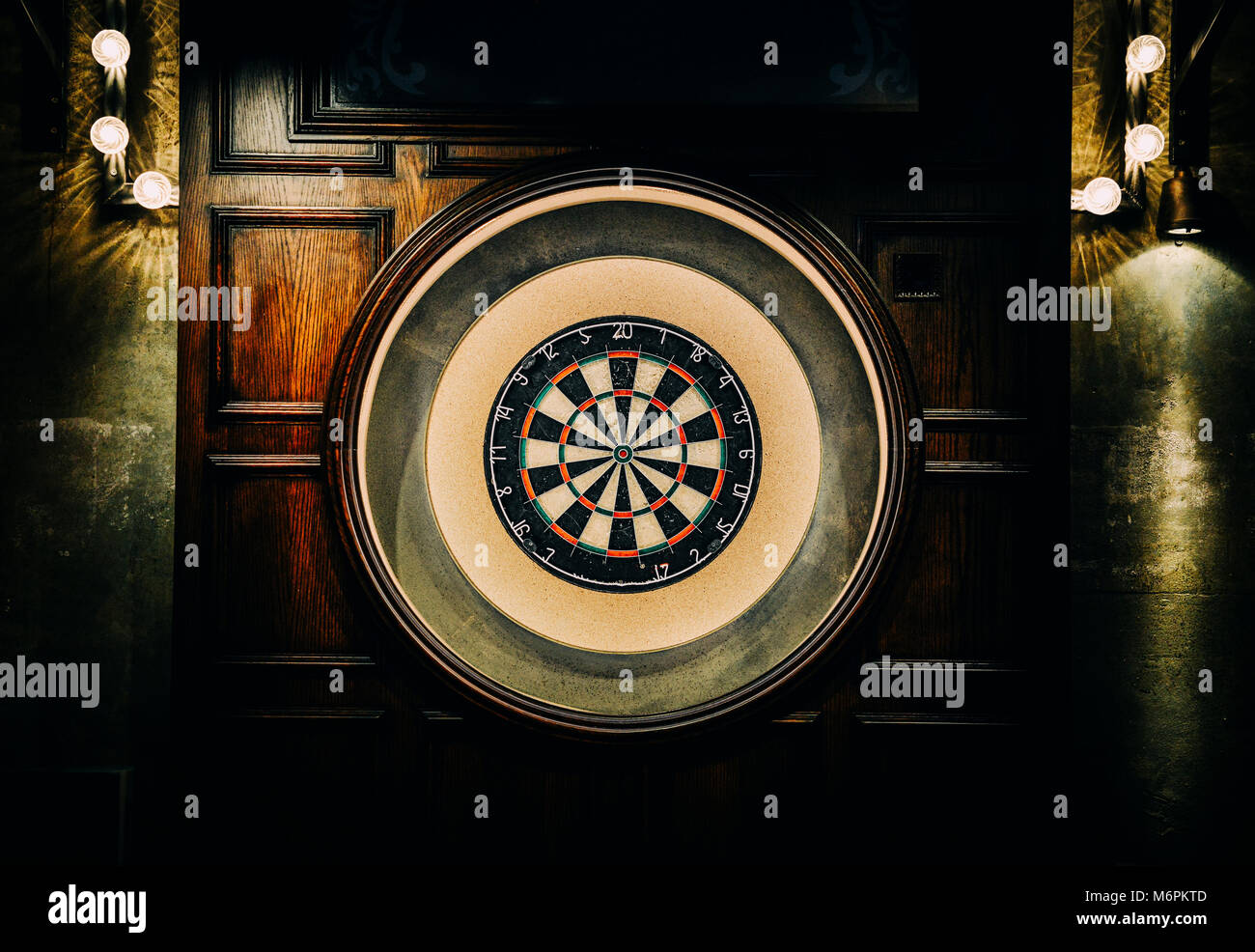 English style dart board with wooden backdrop and faded lights Stock ...
