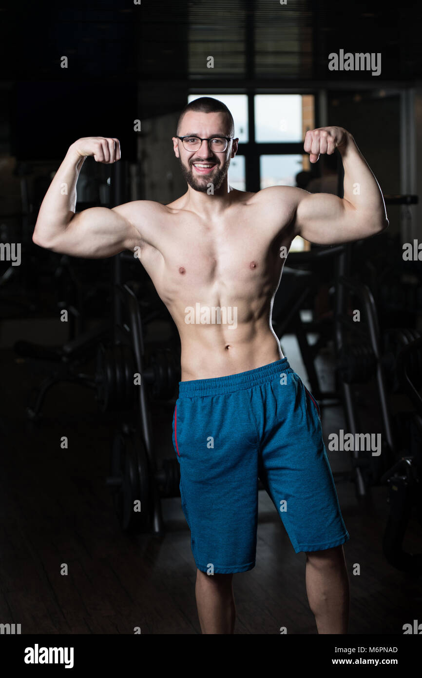 Handsome Geek Man Standing Strong In The Gym And Flexing Muscles ...