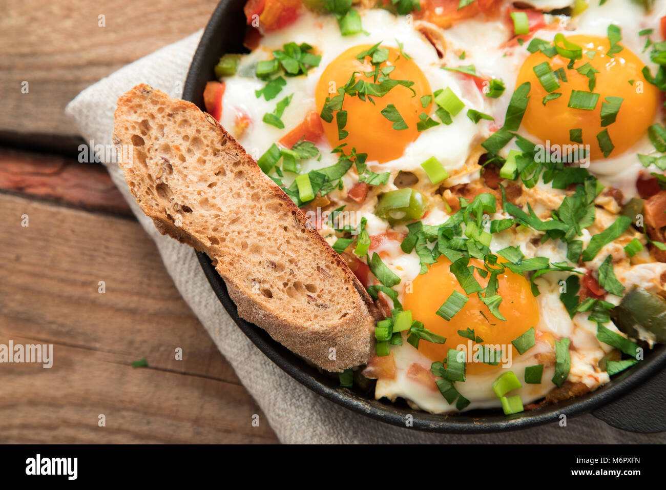 Shakshuka with eggs, tomato, and parsley in a iron pan. Shakshuka ...