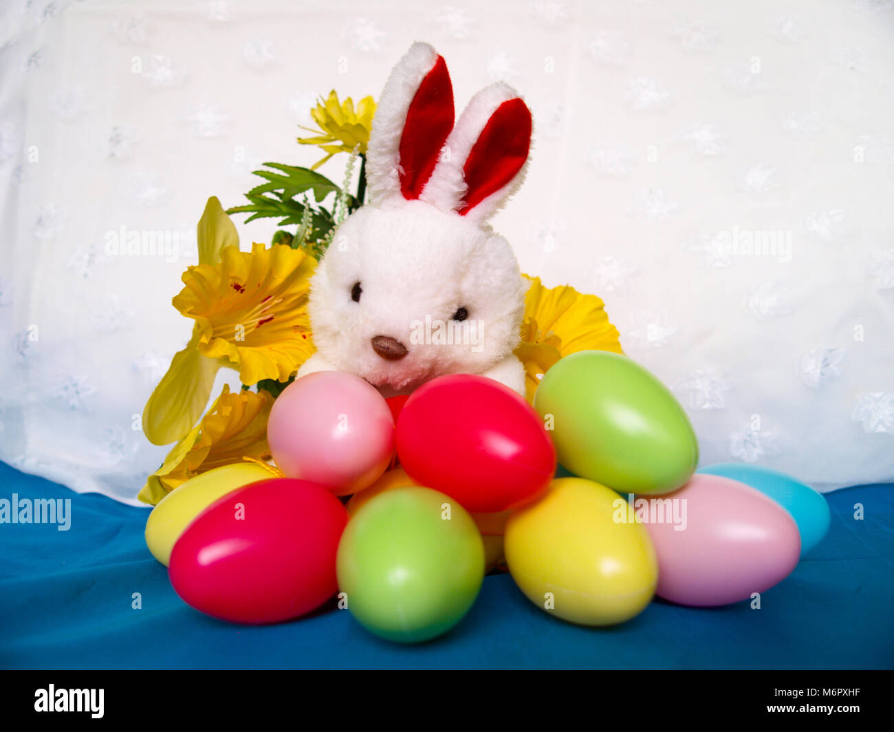 White plush rabbit with colorful Easter eggs and yellow flowers Stock ...