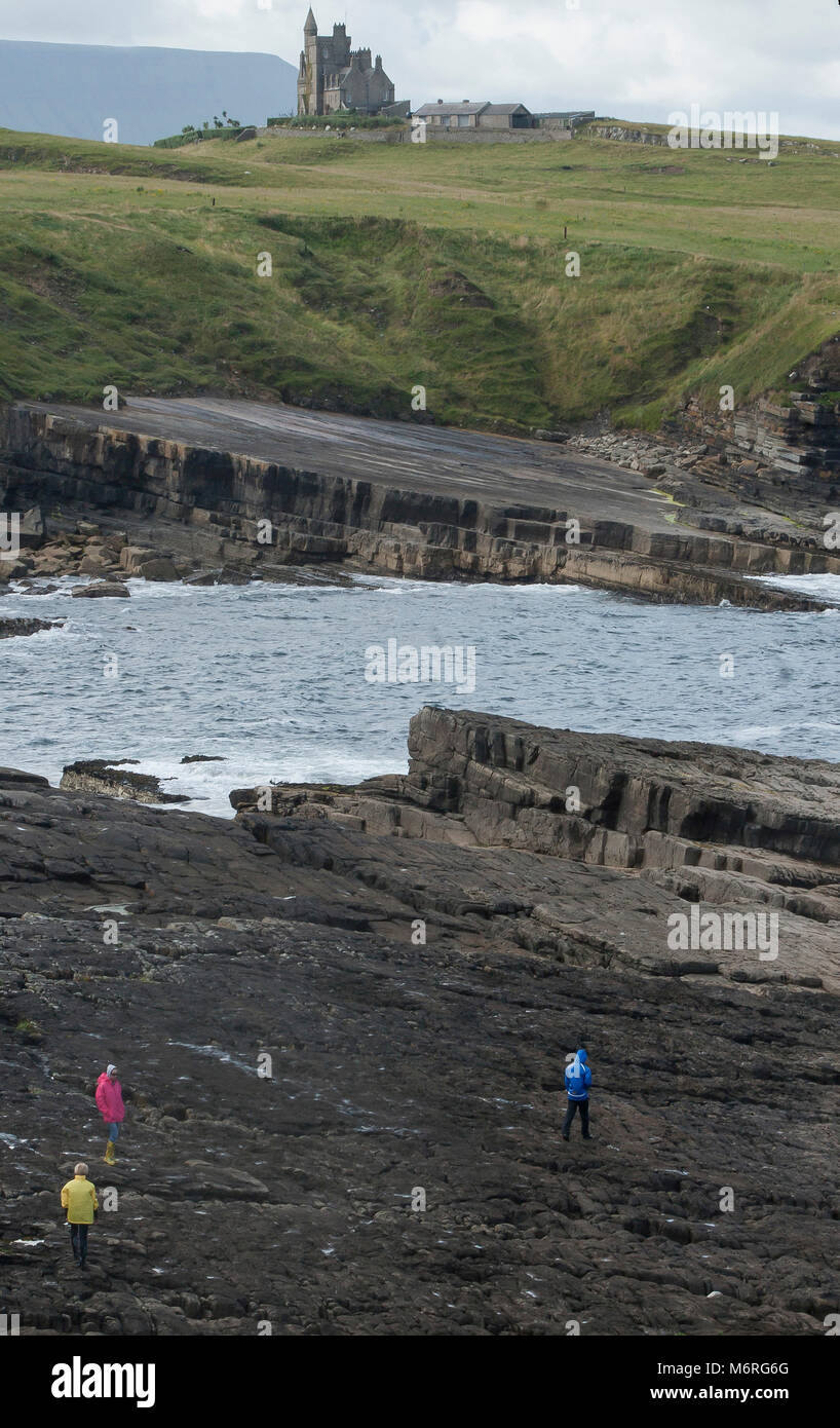 People walking on the rocks at Mullaghmore Head with Classiebawn Castle ...