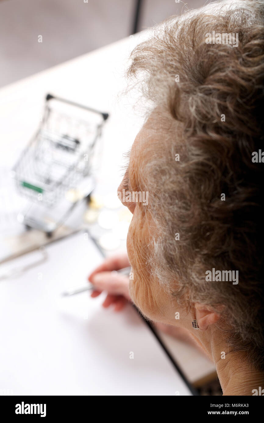 Senior woman between 70 and 80 years old is making some calculation ...