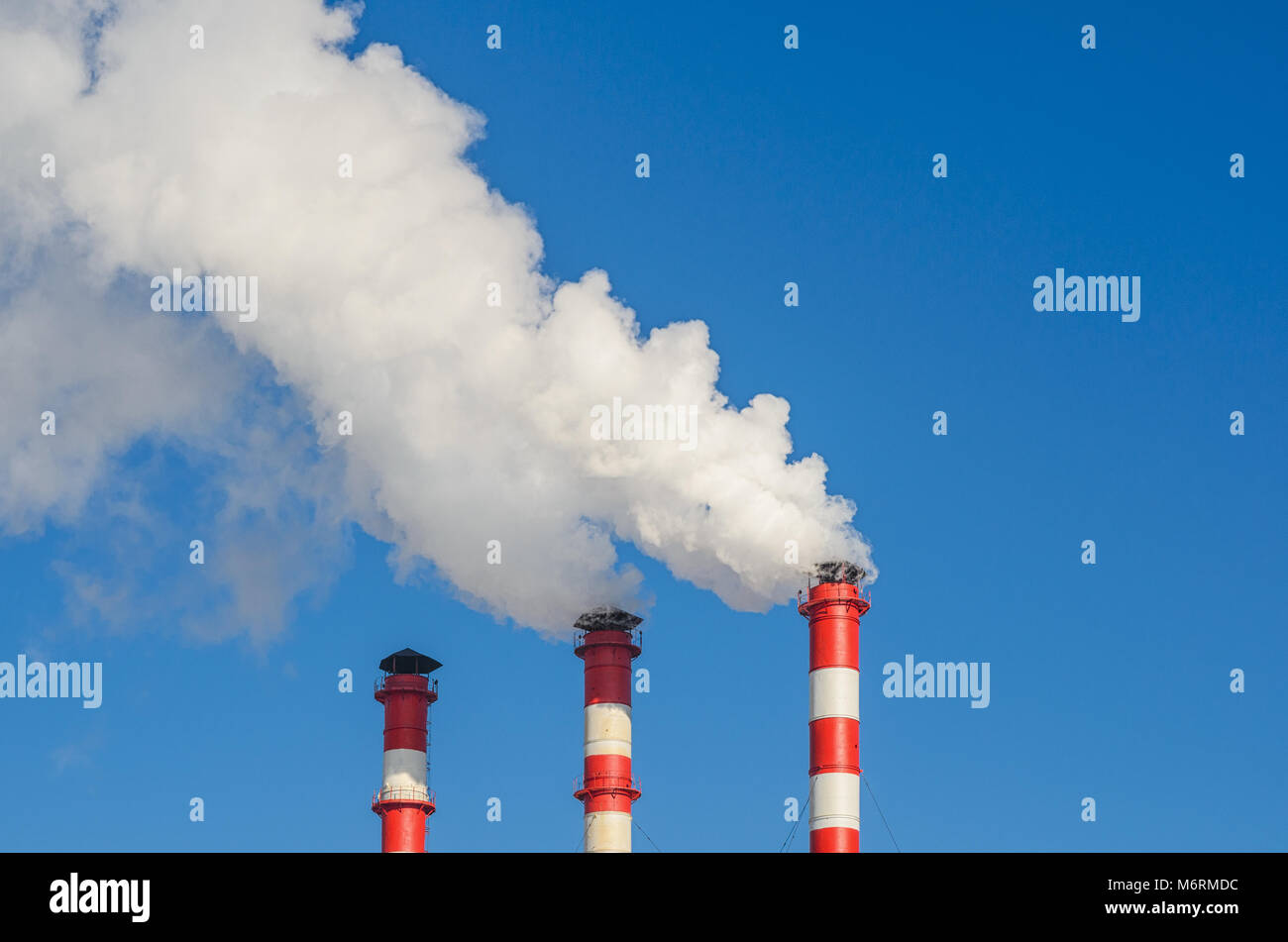 Plant pipes with smoke against clear blue sky Stock Photo - Alamy