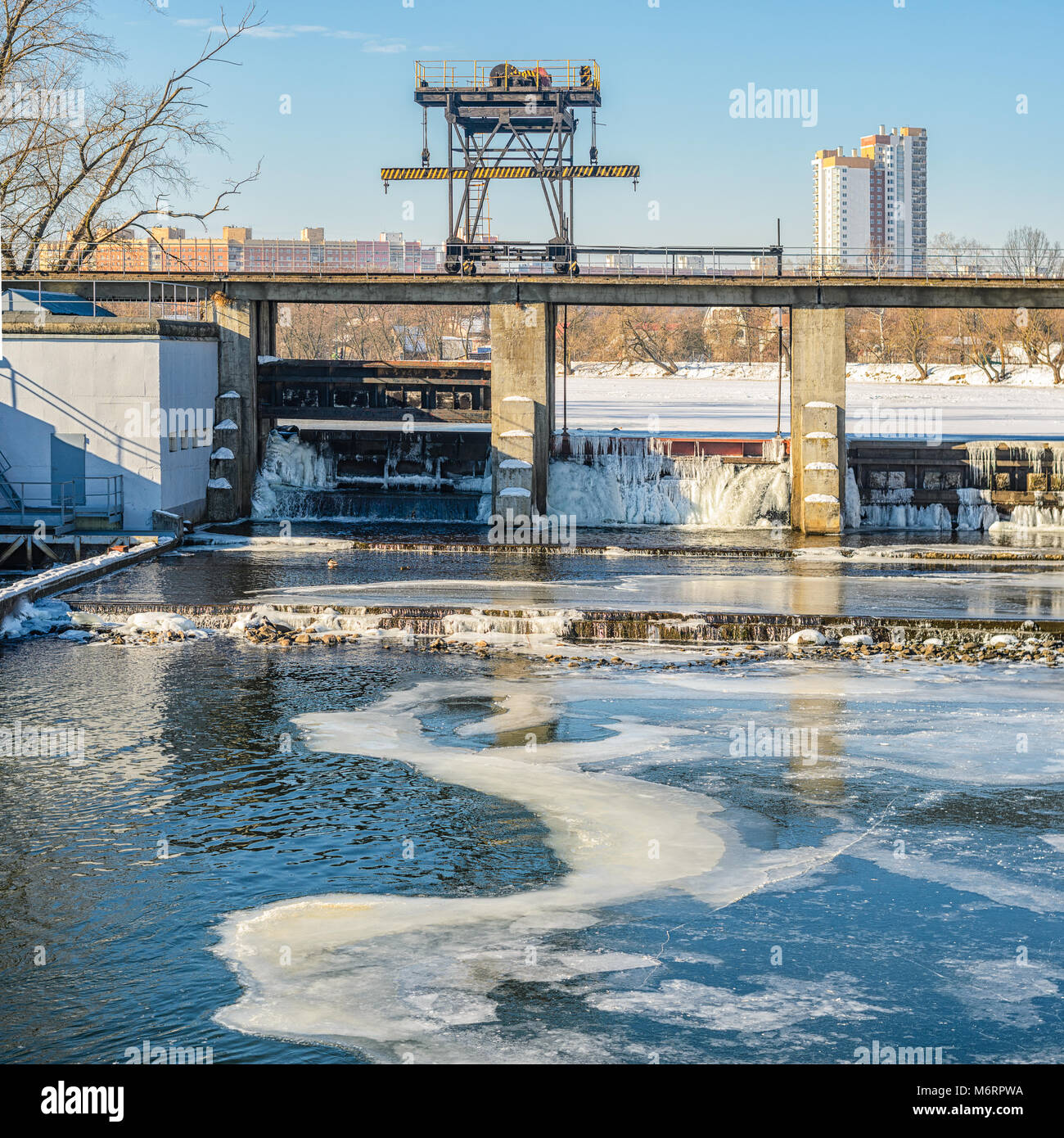 The dam on the river in the city in the winter. Icing of dam structures ...