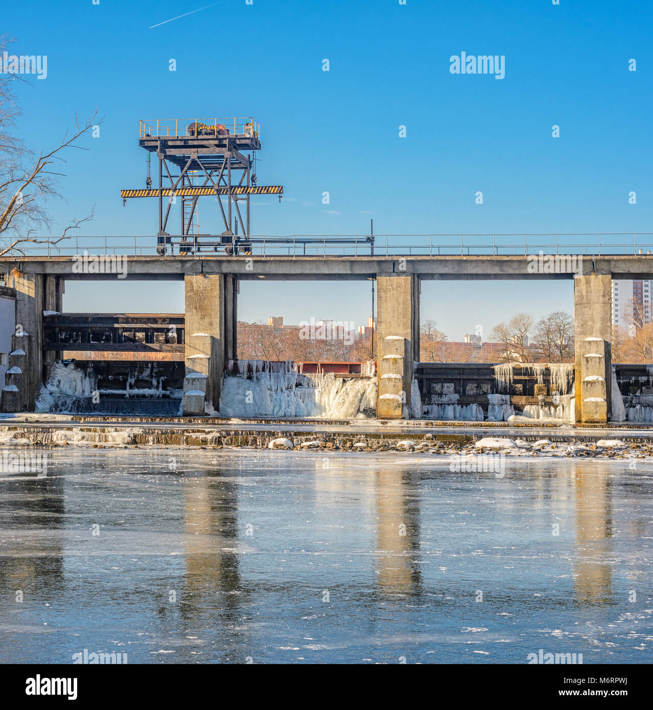 The dam on the river in the city in the winter. Icing of dam structures ...