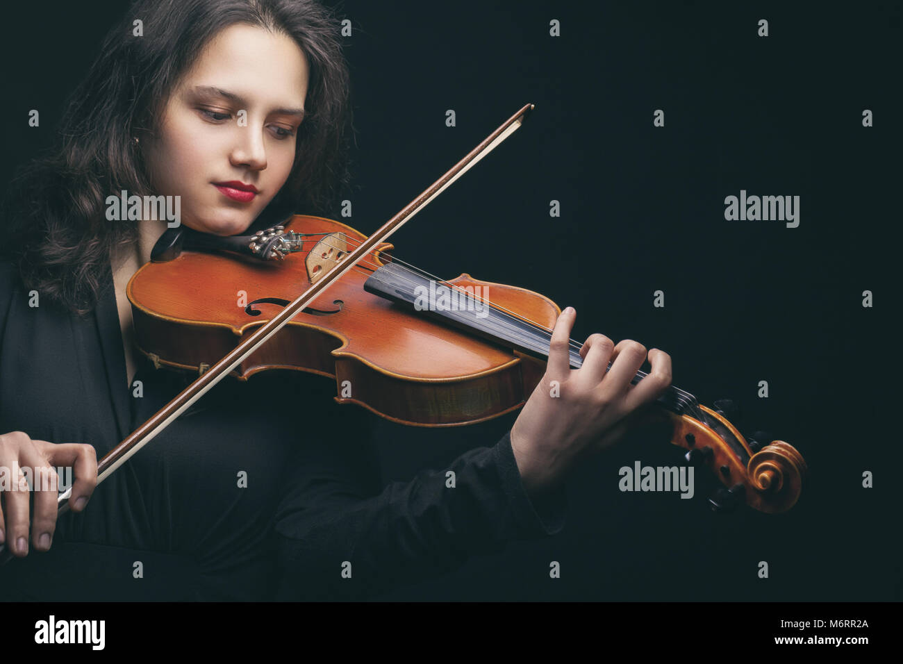 Beautiful young woman playing the violin on dark background Stock Photo ...