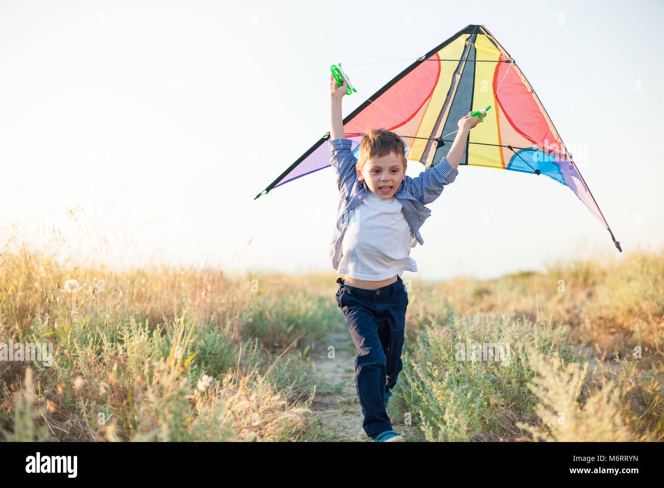 happy beautiful boy running with colorful kite in his hands overhead ...
