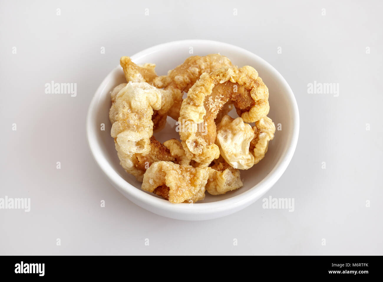 Crispy pork skin (pork rind) in the small bowl, white background - top ...