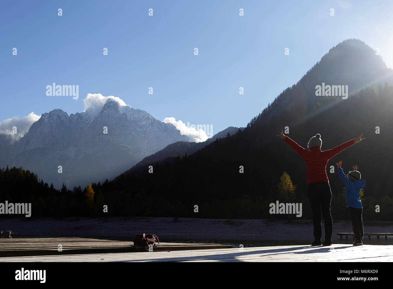 Mother and child raising hands at lake Jasna, mountain lake in north ...