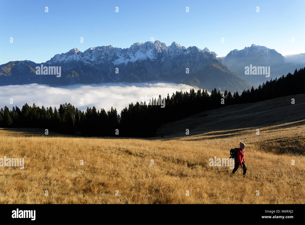 Woman hiking on a mountain, covered with grass, with a beautiful view ...