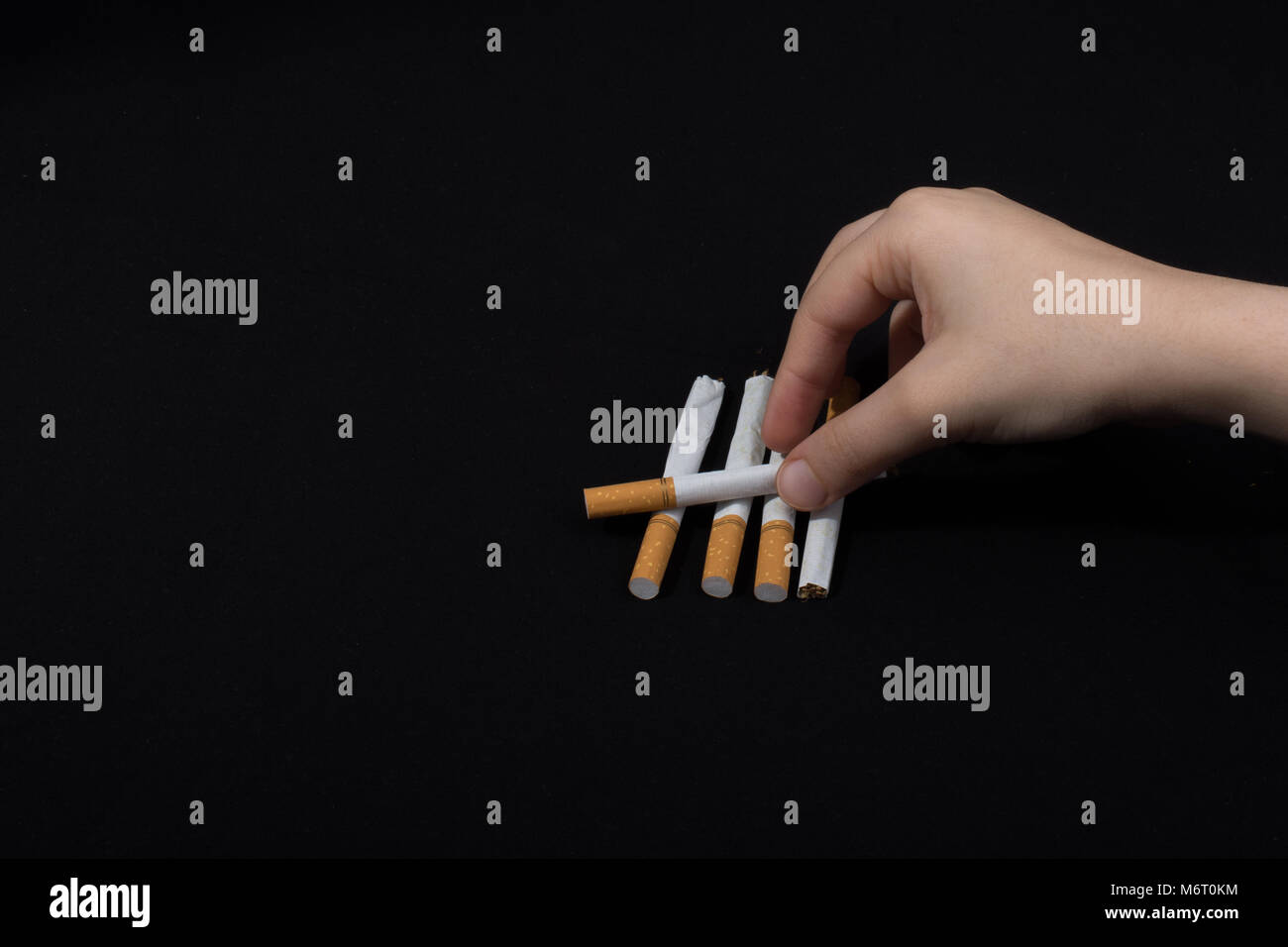 Hand is holding crossed cigarettes on black background Stock Photo - Alamy